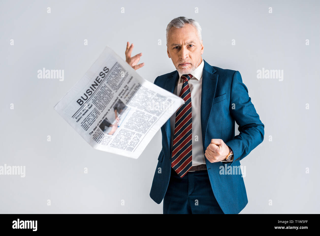 angry mature man in formal wear throwing business newspaper while ...