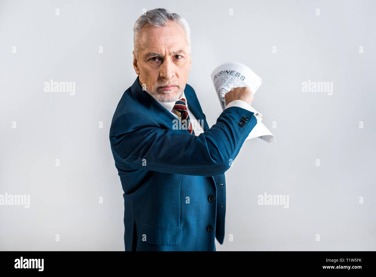 angry mature businessman holding business newspaper isolated on grey ...