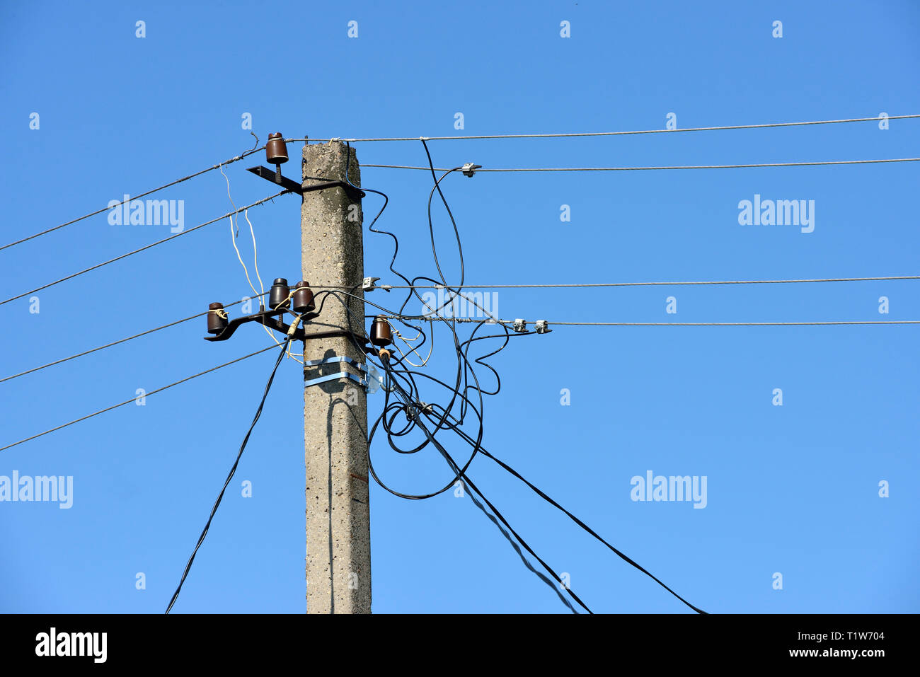 Close-up upper part of utility pole with many electric wires and insulators in bright morning ...
