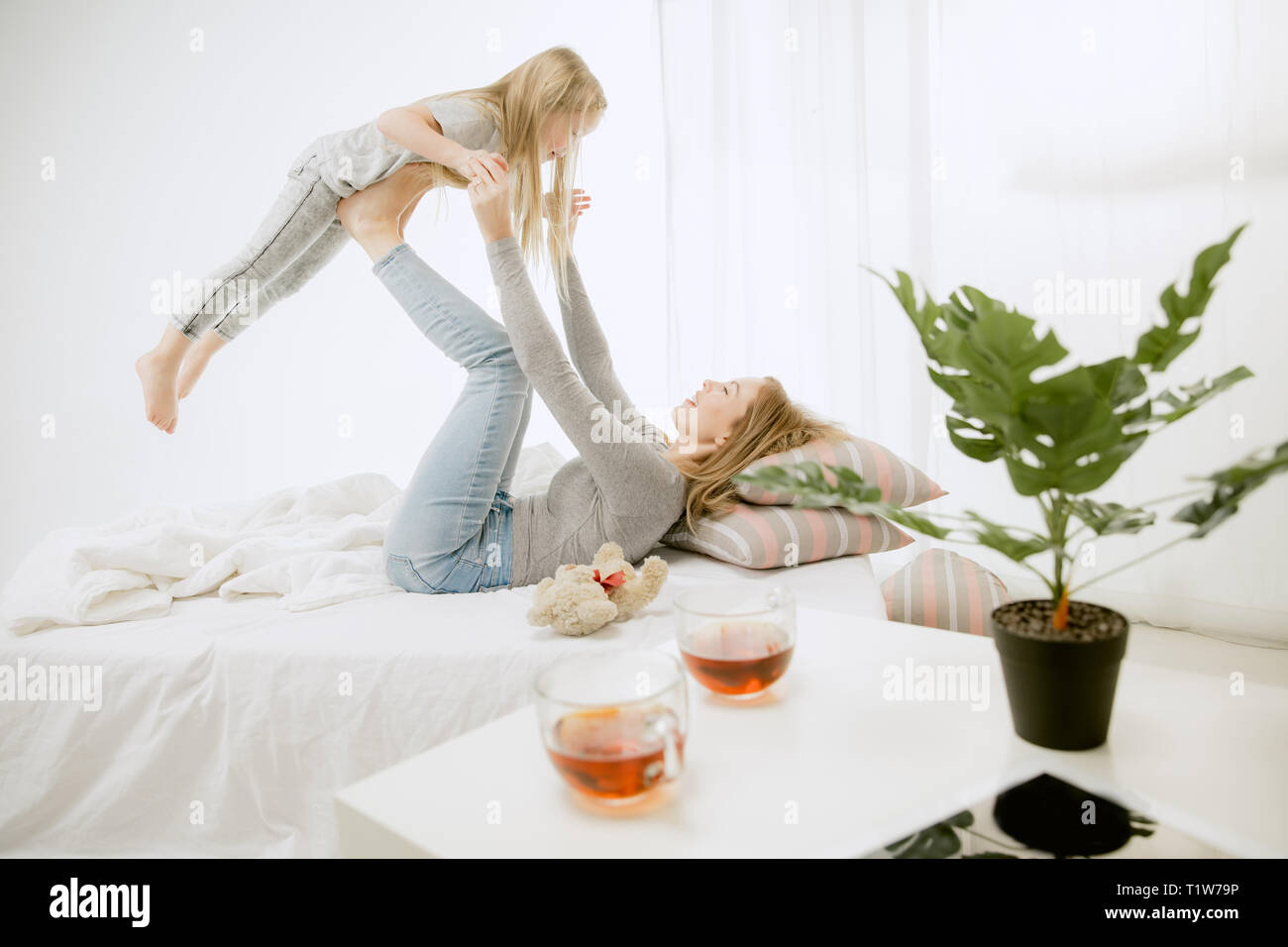 Young mother and her little daughter at home at sunny morning. Soft ...