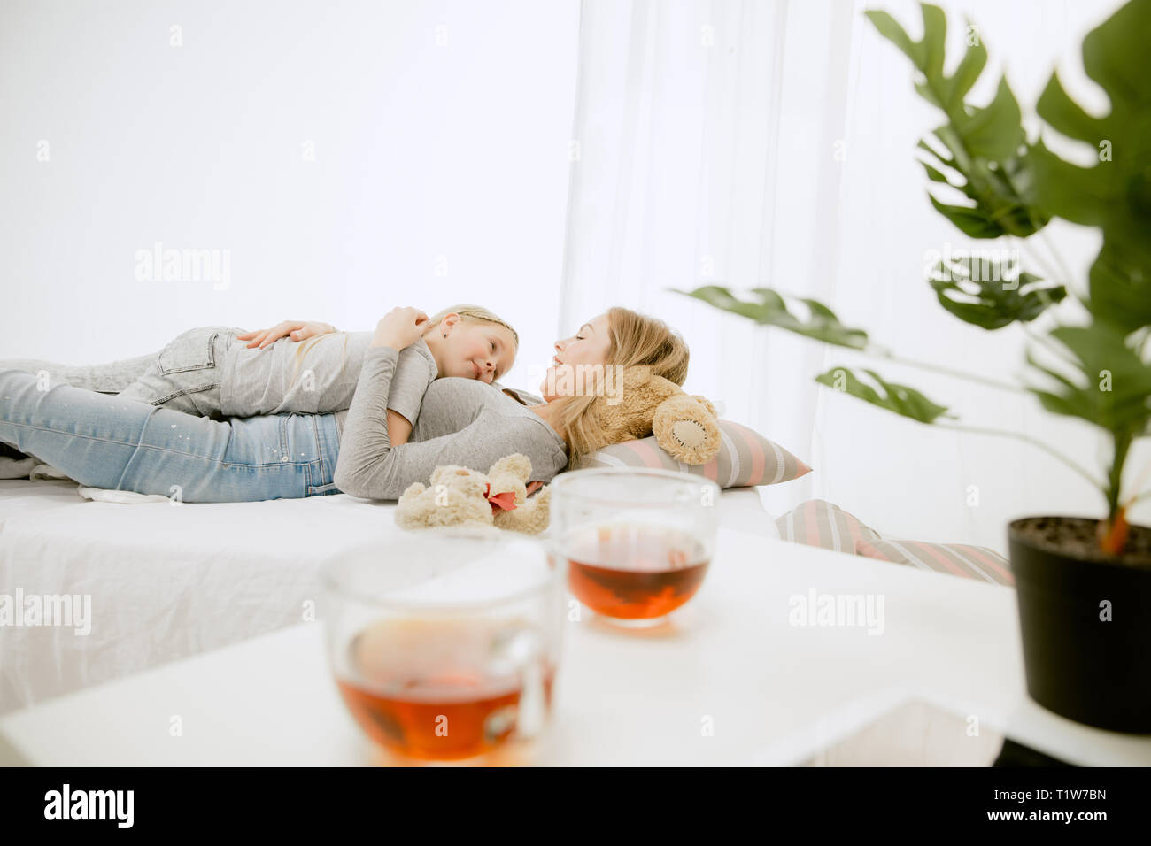 Young mother and her little daughter at home at sunny morning. Soft ...