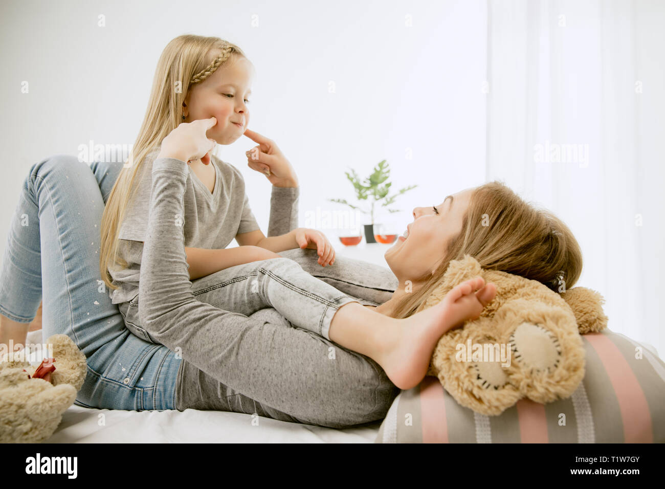 Young mother and her little daughter at home at sunny morning. Soft ...