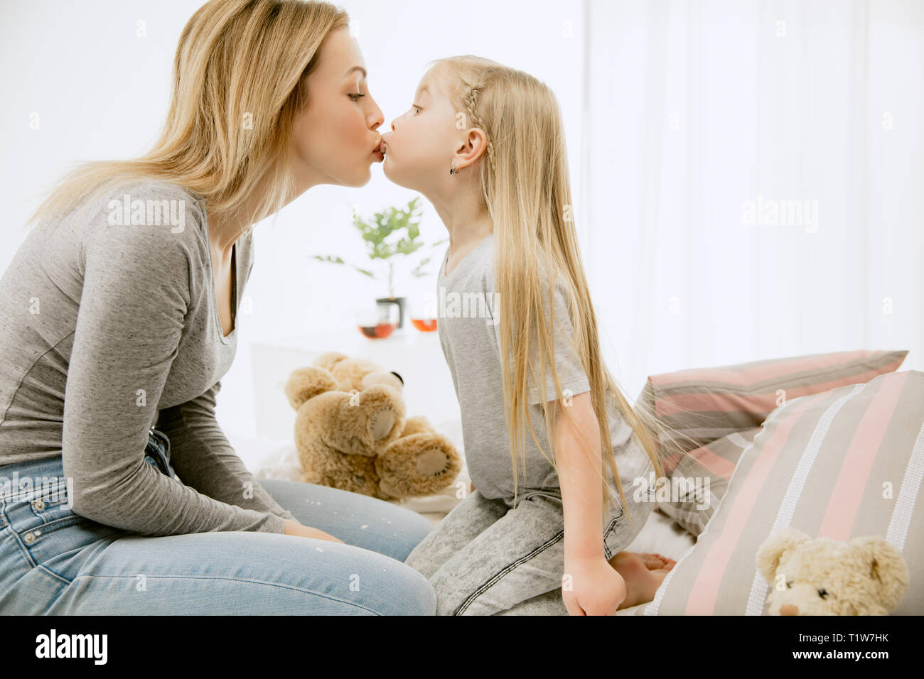 Young mother and her little daughter at home at sunny morning. Soft ...