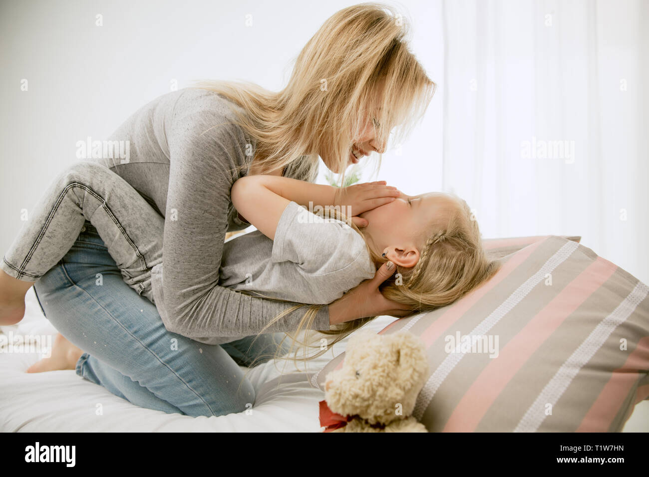 Young mother and her little daughter at home at sunny morning. Soft ...