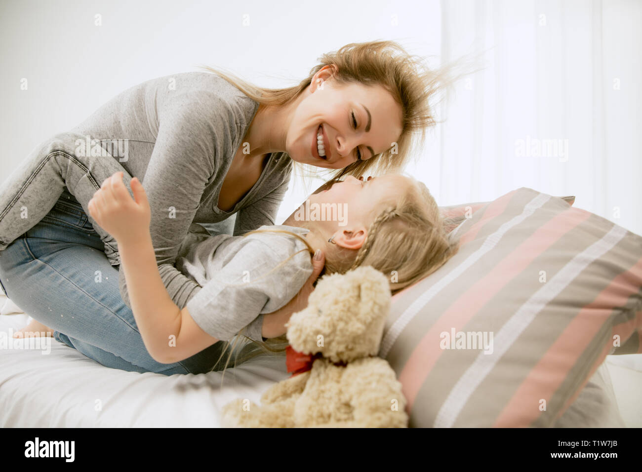 Young mother and her little daughter at home at sunny morning. Soft ...