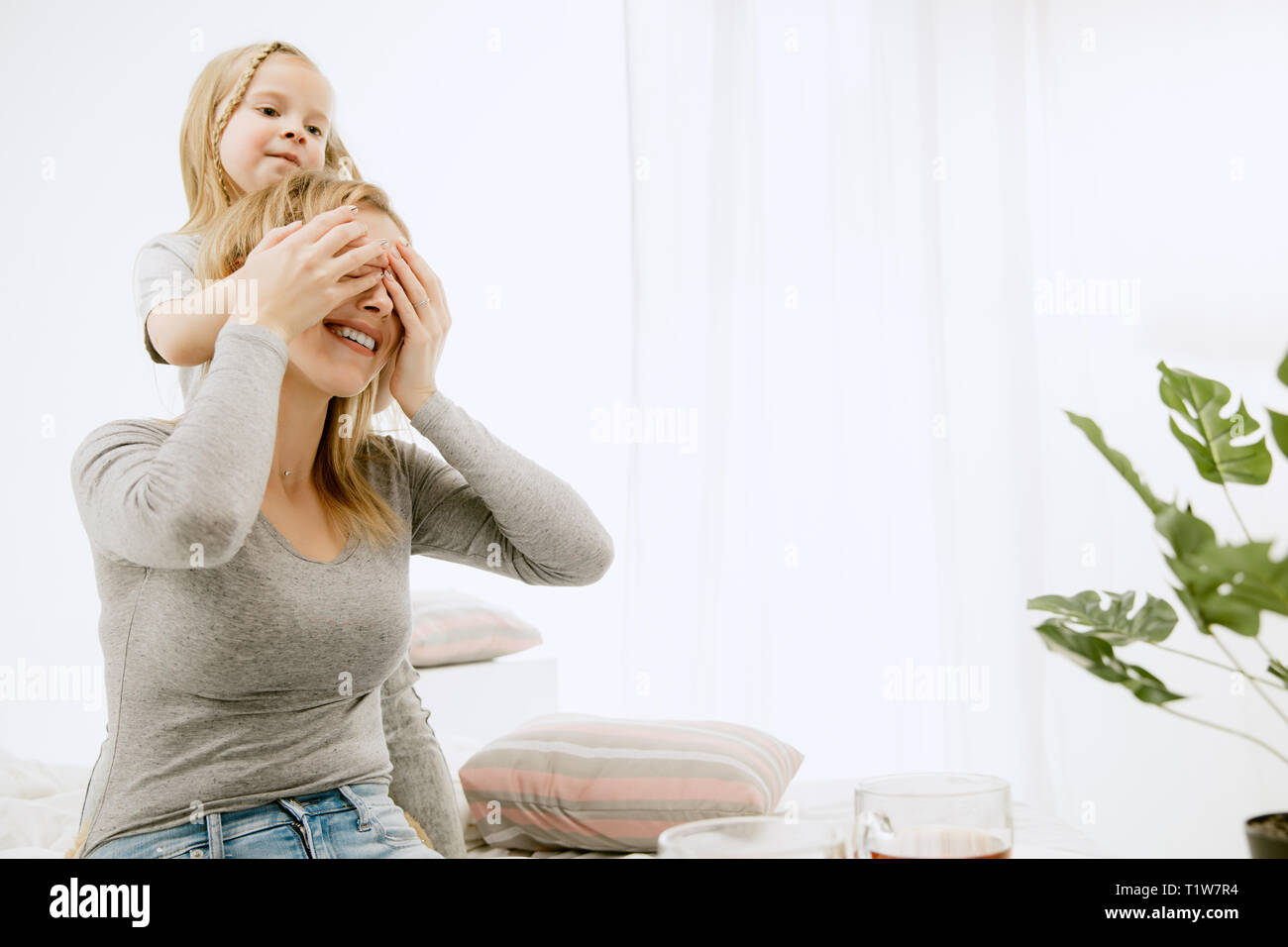 Young mother and her little daughter at home at sunny morning. Soft ...