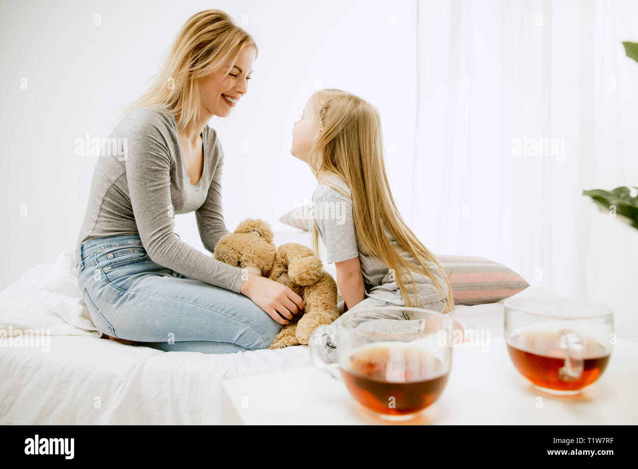 Young mother and her little daughter at home at sunny morning. Soft ...