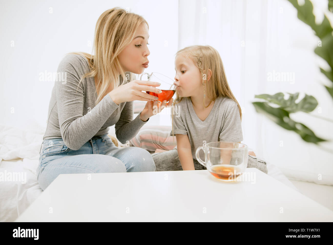 Young mother and her little daughter at home at sunny morning. Soft ...