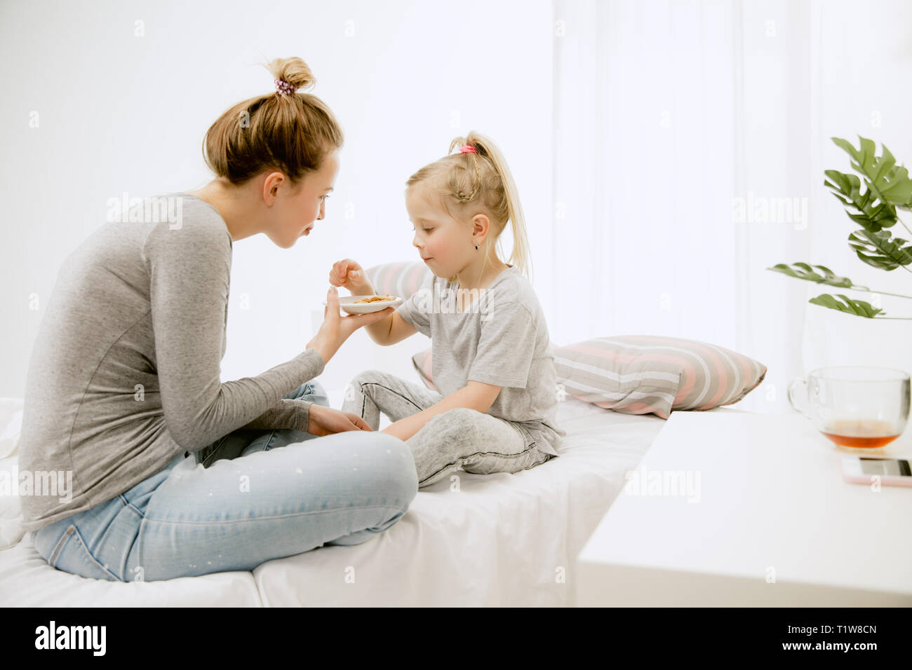 Young mother and her little daughter at home at sunny morning. Soft ...
