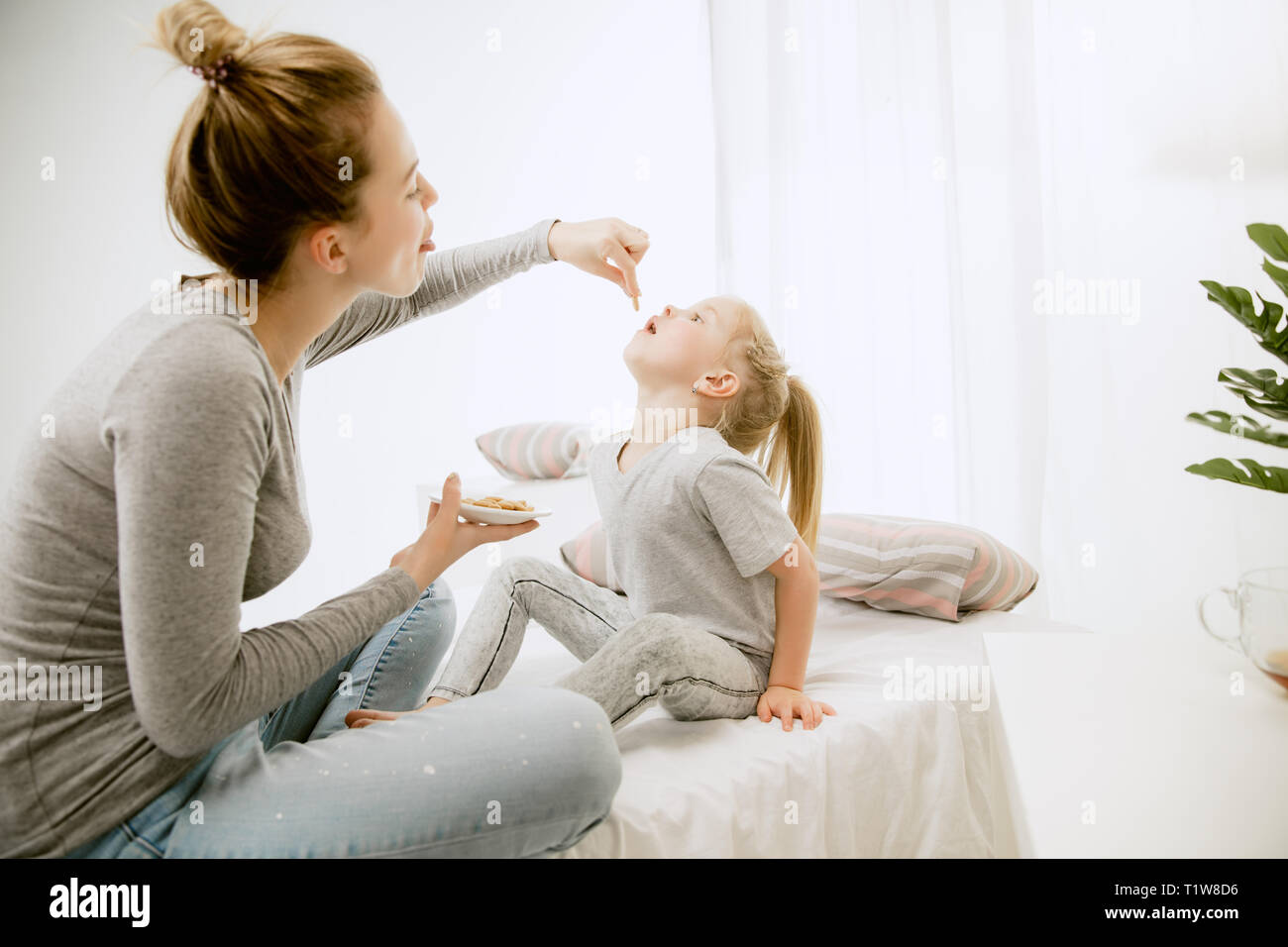 Young mother and her little daughter at home at sunny morning. Soft ...