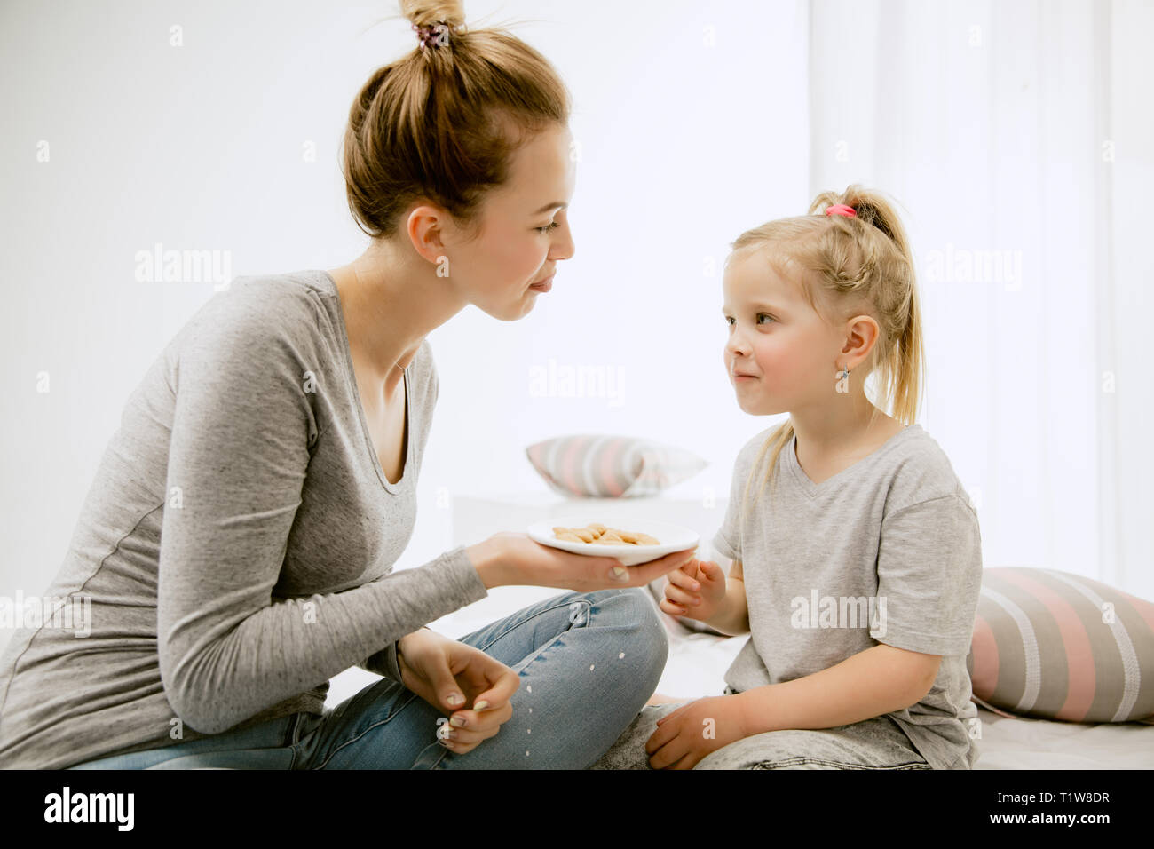 Young mother and her little daughter at home at sunny morning. Soft ...