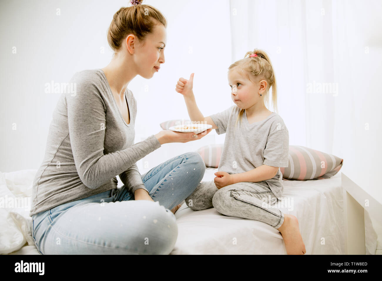 Young mother and her little daughter at home at sunny morning. Soft ...