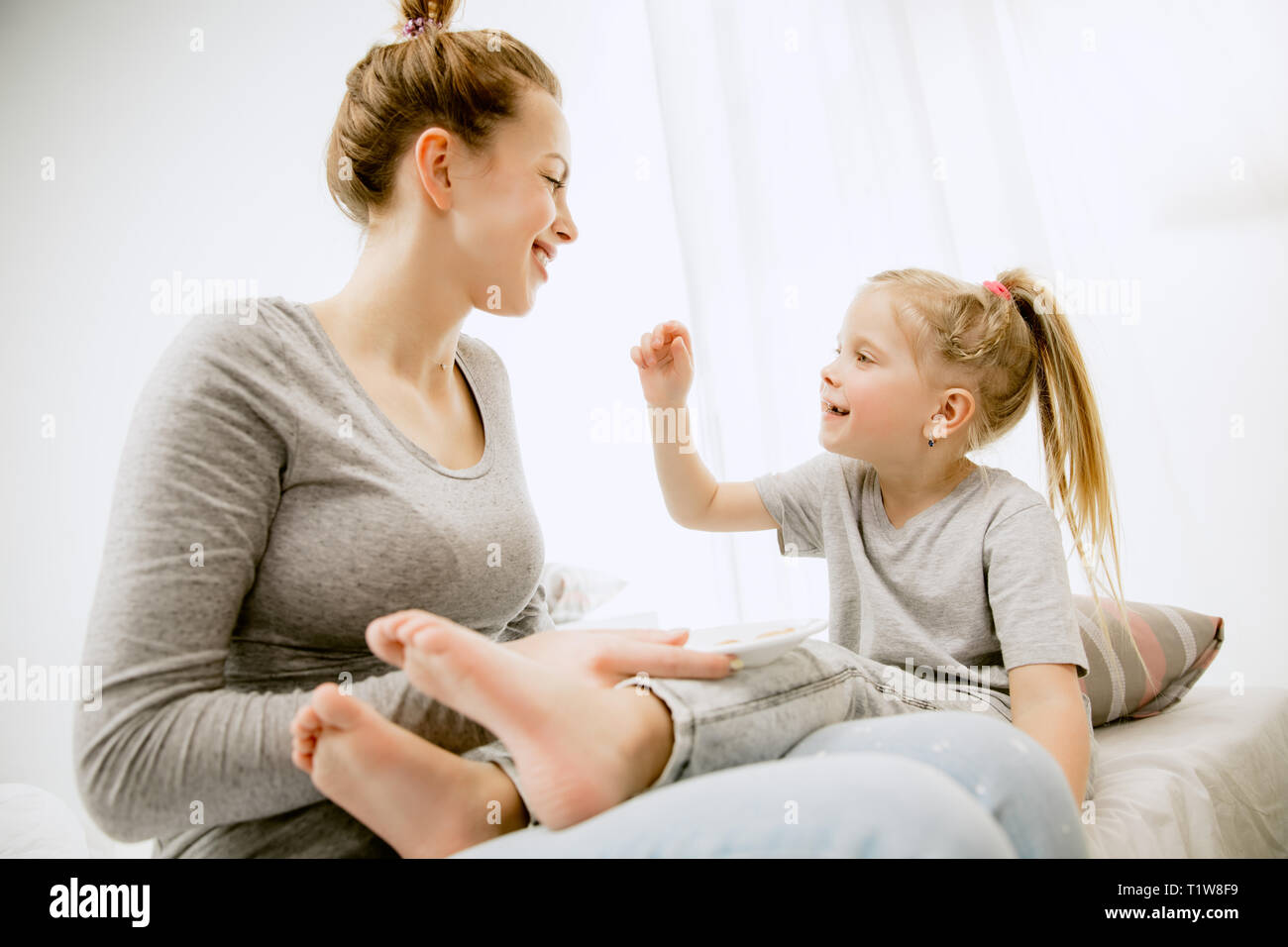 Young mother and her little daughter at home at sunny morning. Soft ...