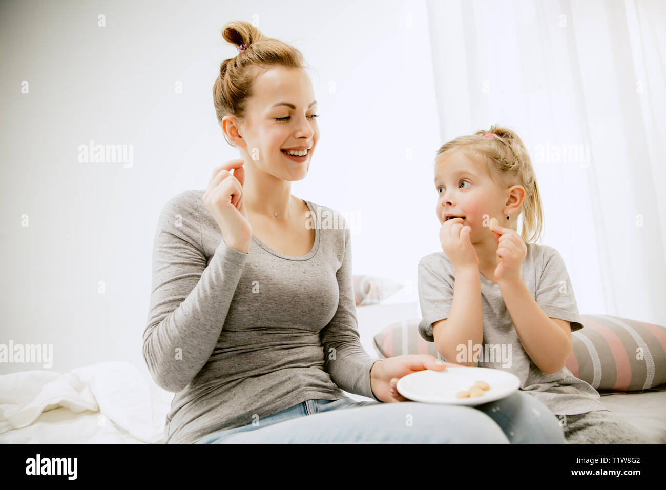 Young mother and her little daughter at home at sunny morning. Soft ...