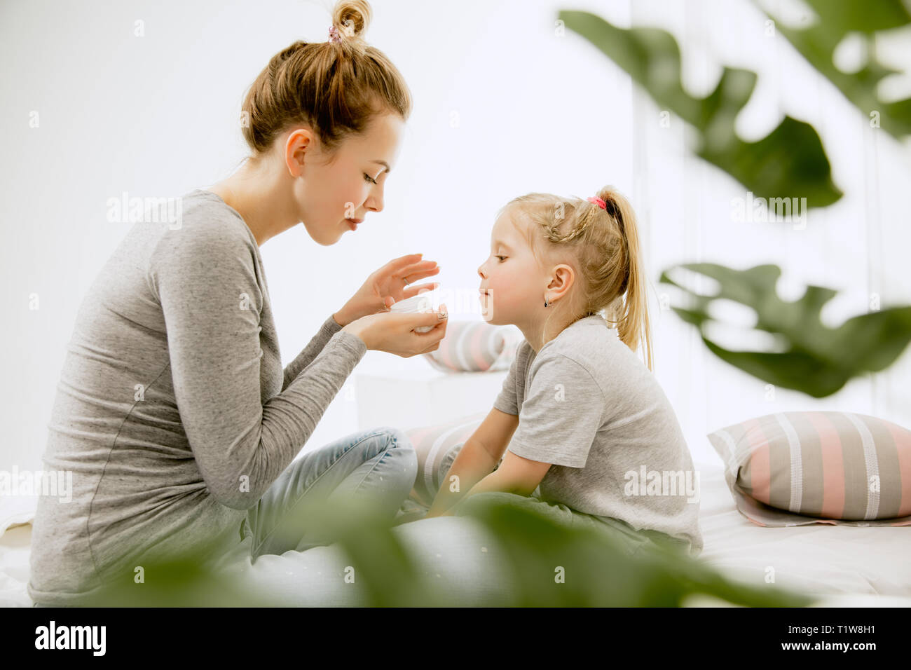 Young mother and her little daughter at home at sunny morning. Soft ...