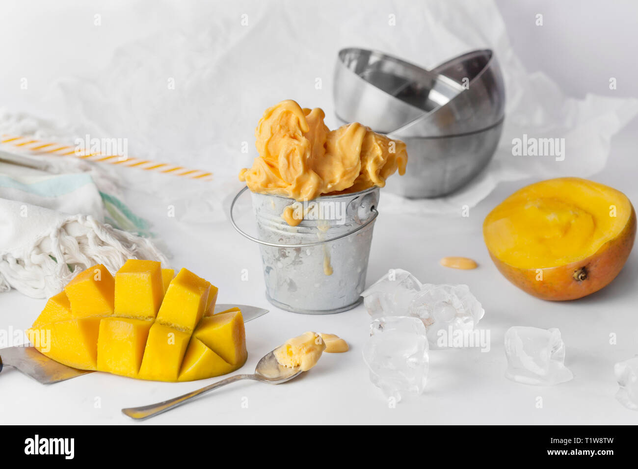 Mango ice cream in a metal mini bucket decorated with sliced mango ...