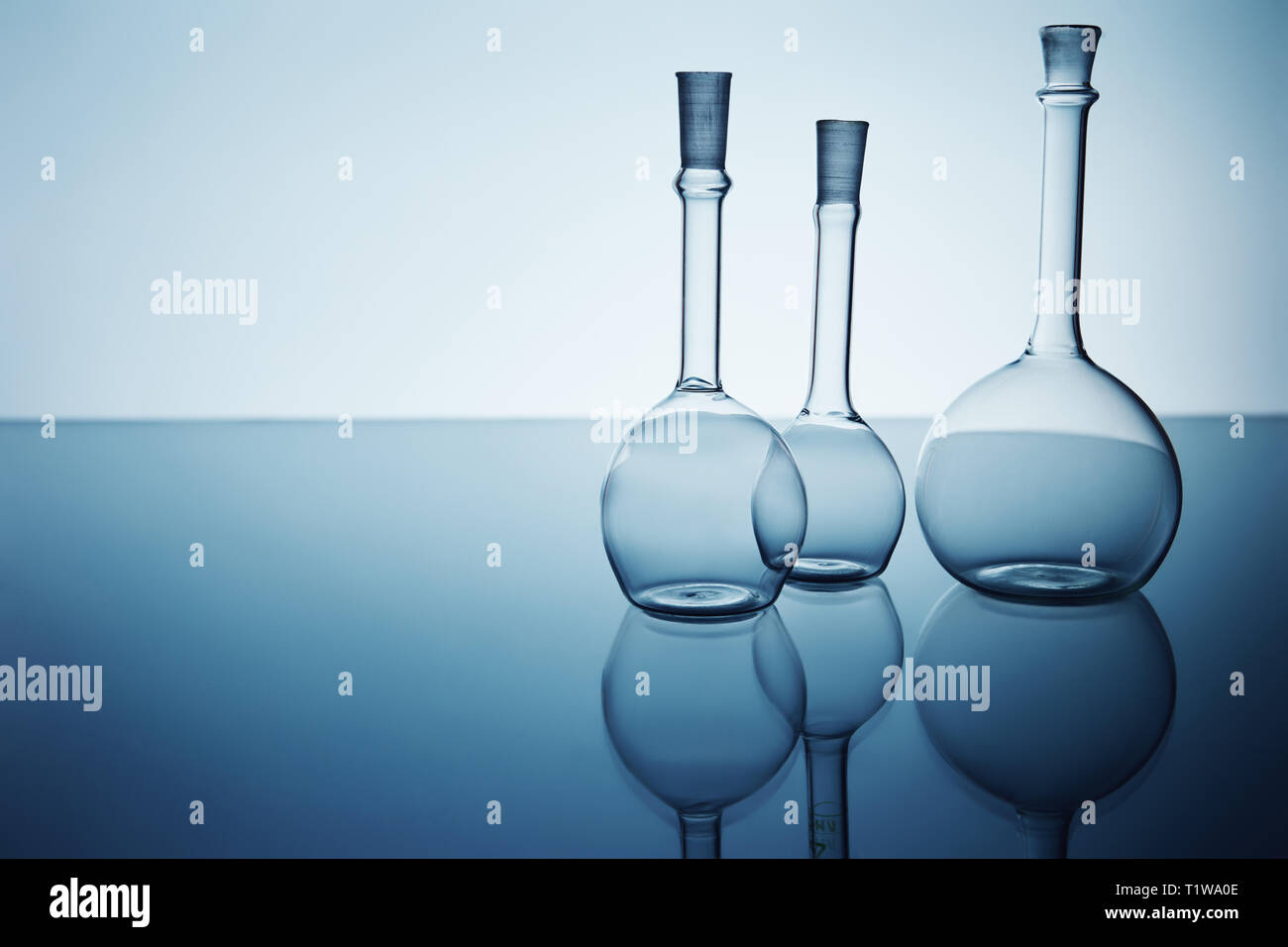 three beakers in backlight, reflection, blue background Stock Photo - Alamy