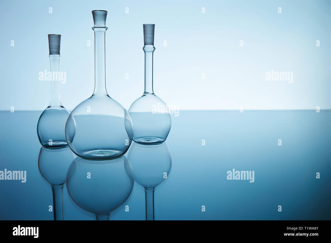 three beakers in backlight, reflection, blue background Stock Photo - Alamy