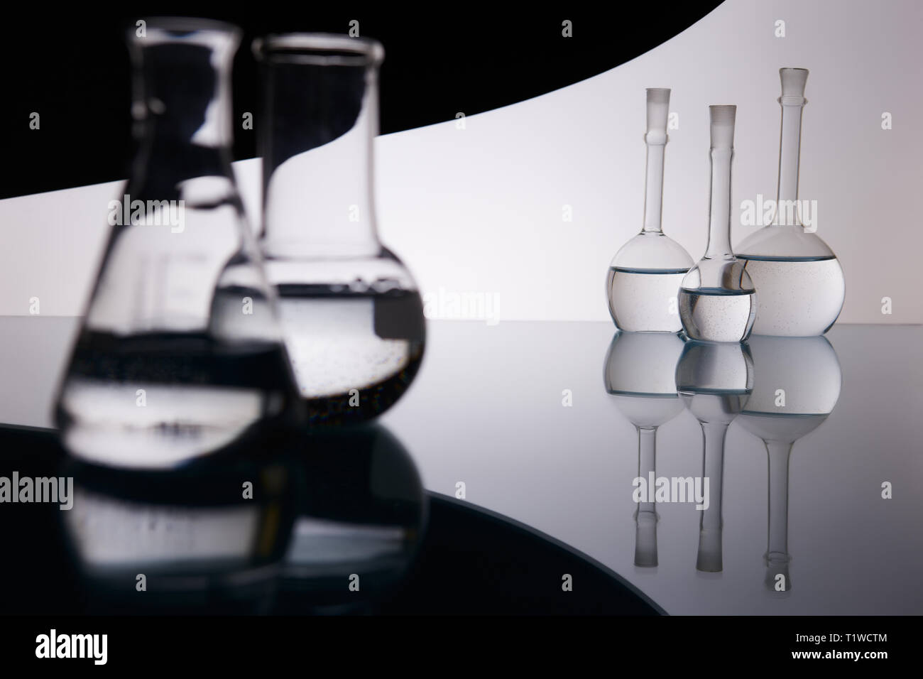 many beakers are in row, with liquid, in backlight, reflection, blue ...