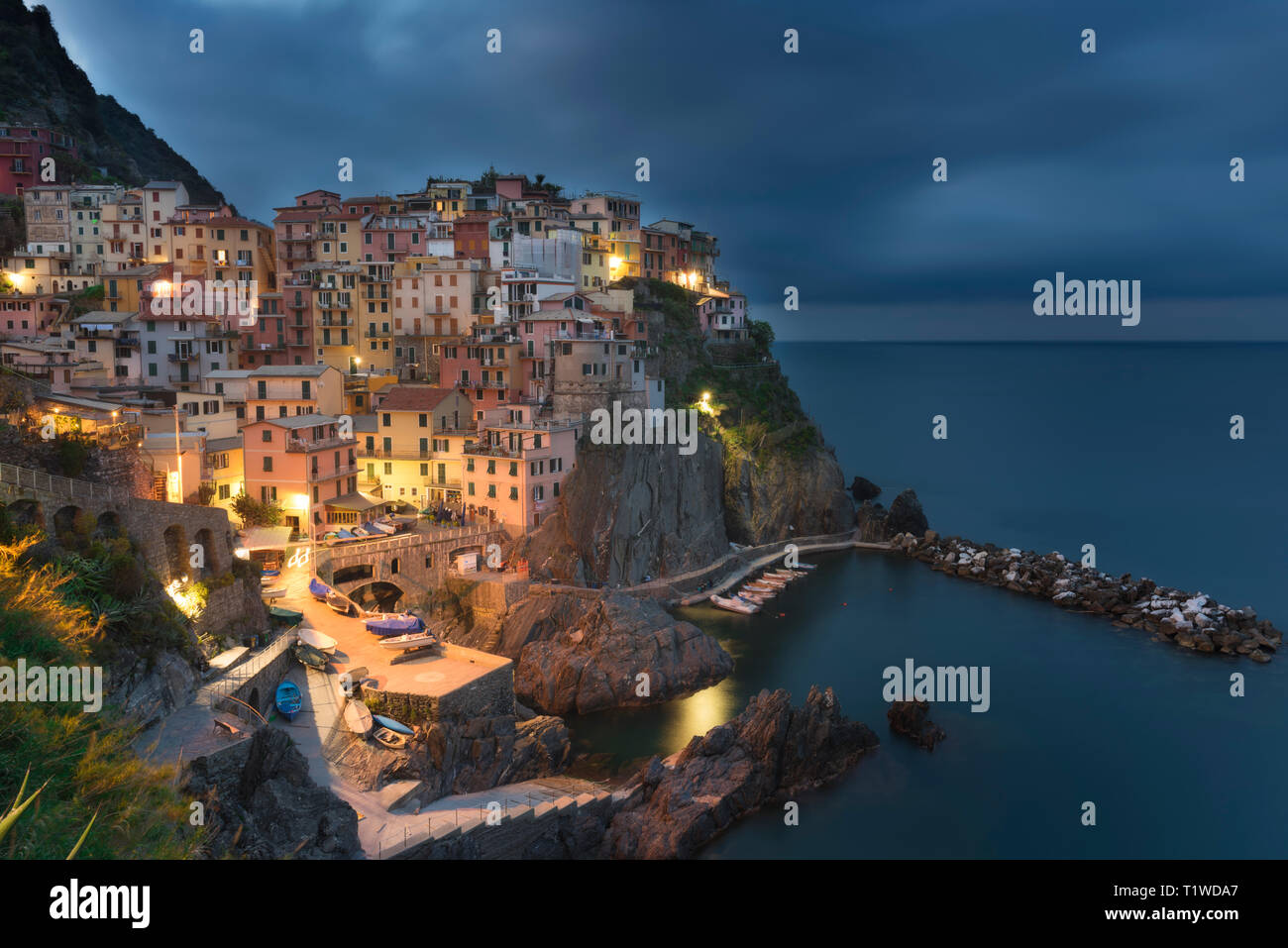 Amazing view of Manarola city at evening light with costal rocks on a ...