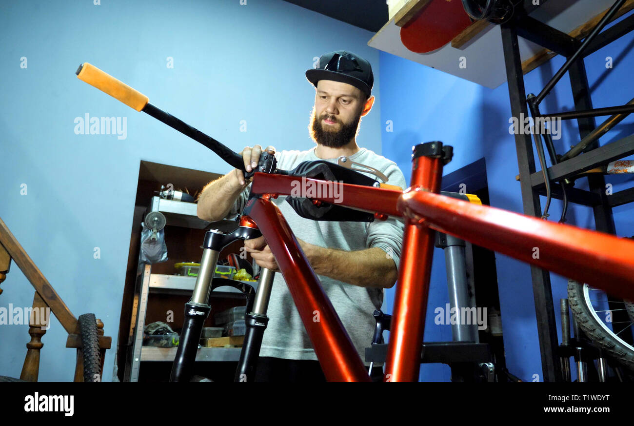 A man bike mechanic assembles a mountain bike in his workshop. A man ...