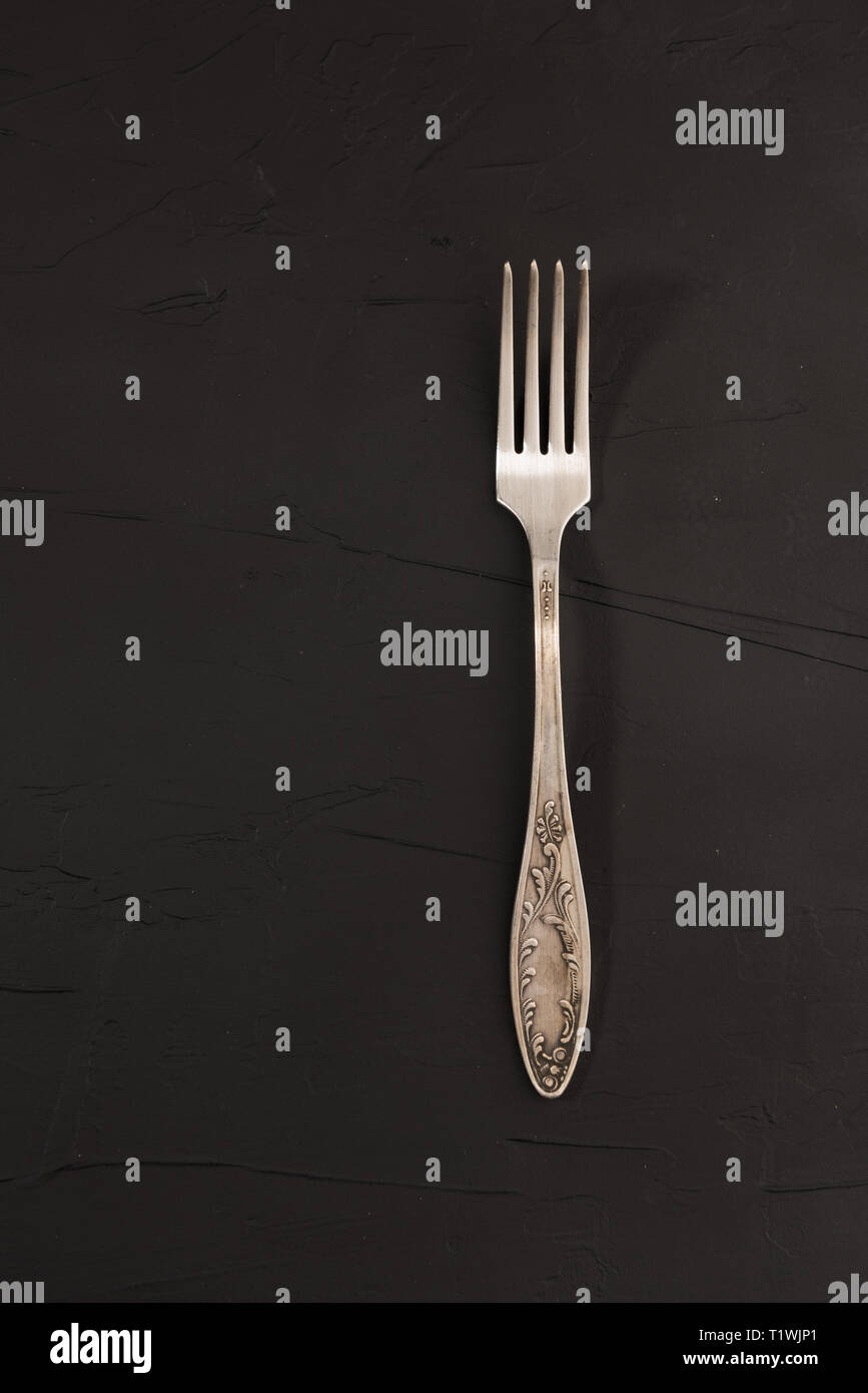 Very old rusty vintage silver fork on a black cement texture background ...