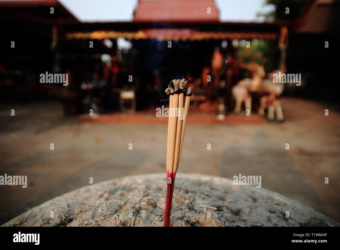 incense sticks burning in front of small local shrine. oriental Thai style worship of local god ...