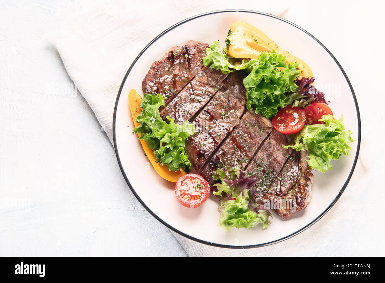 Grilled beef steak and fresh vegetables on plate. Top view with copy ...