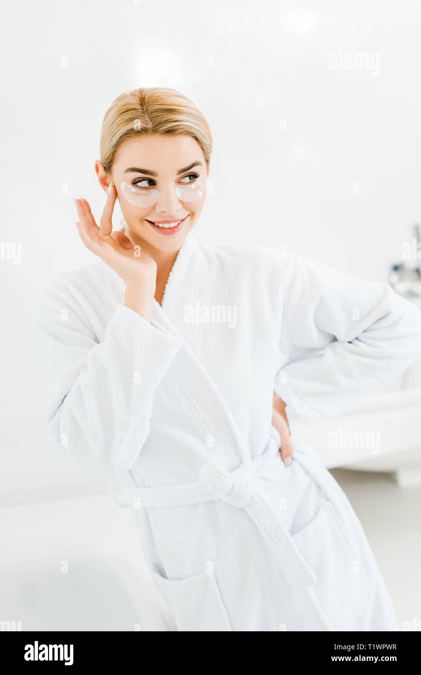 Beautiful And Smiling Woman In White Bathrobe With Eye Patches On Face