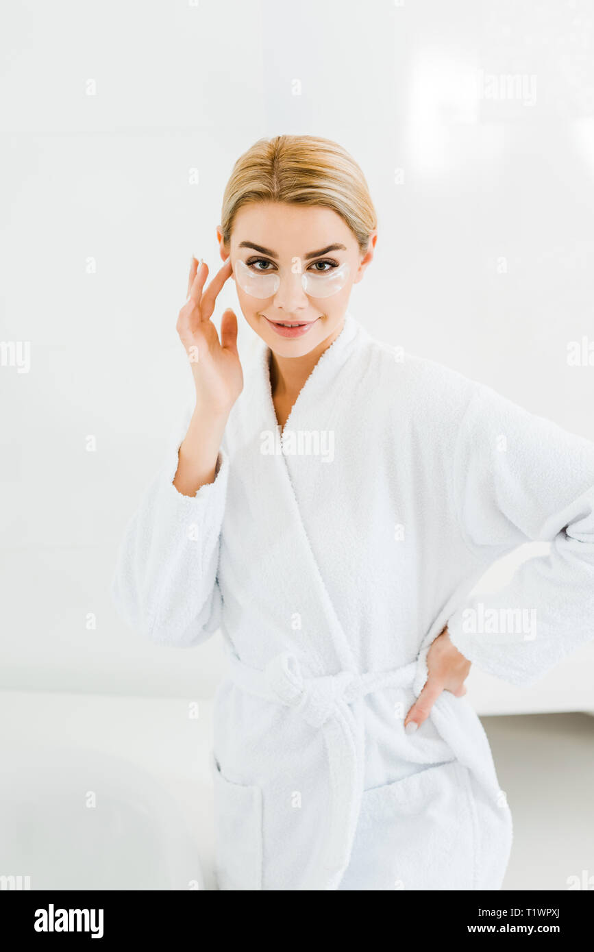 beautiful and blonde woman in white bathrobe with eye patches on face ...