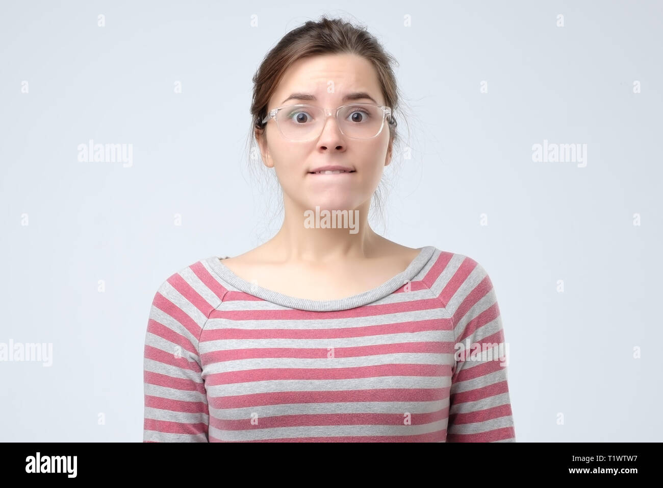 Young woman biting lips with fear facial expression Stock Photo - Alamy