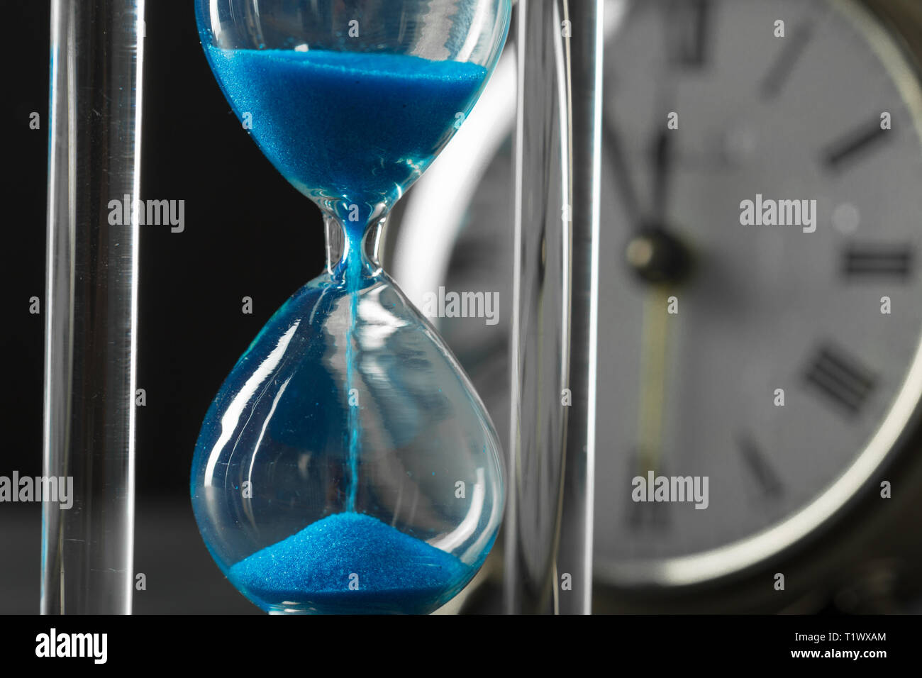 Time is passing. Blue hourglass close up Stock Photo - Alamy