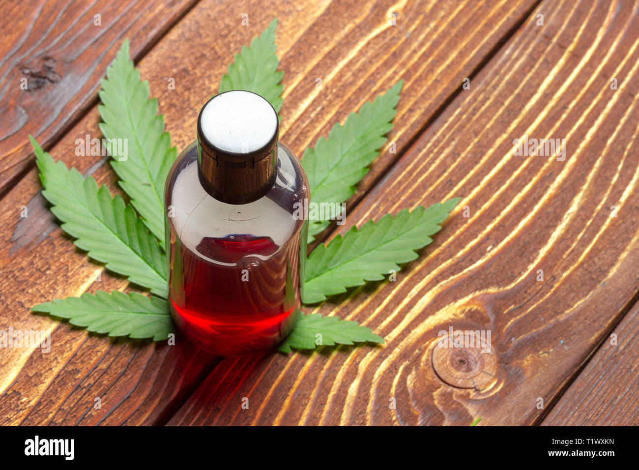Cannabis leaves and oil on wooden background Stock Photo - Alamy