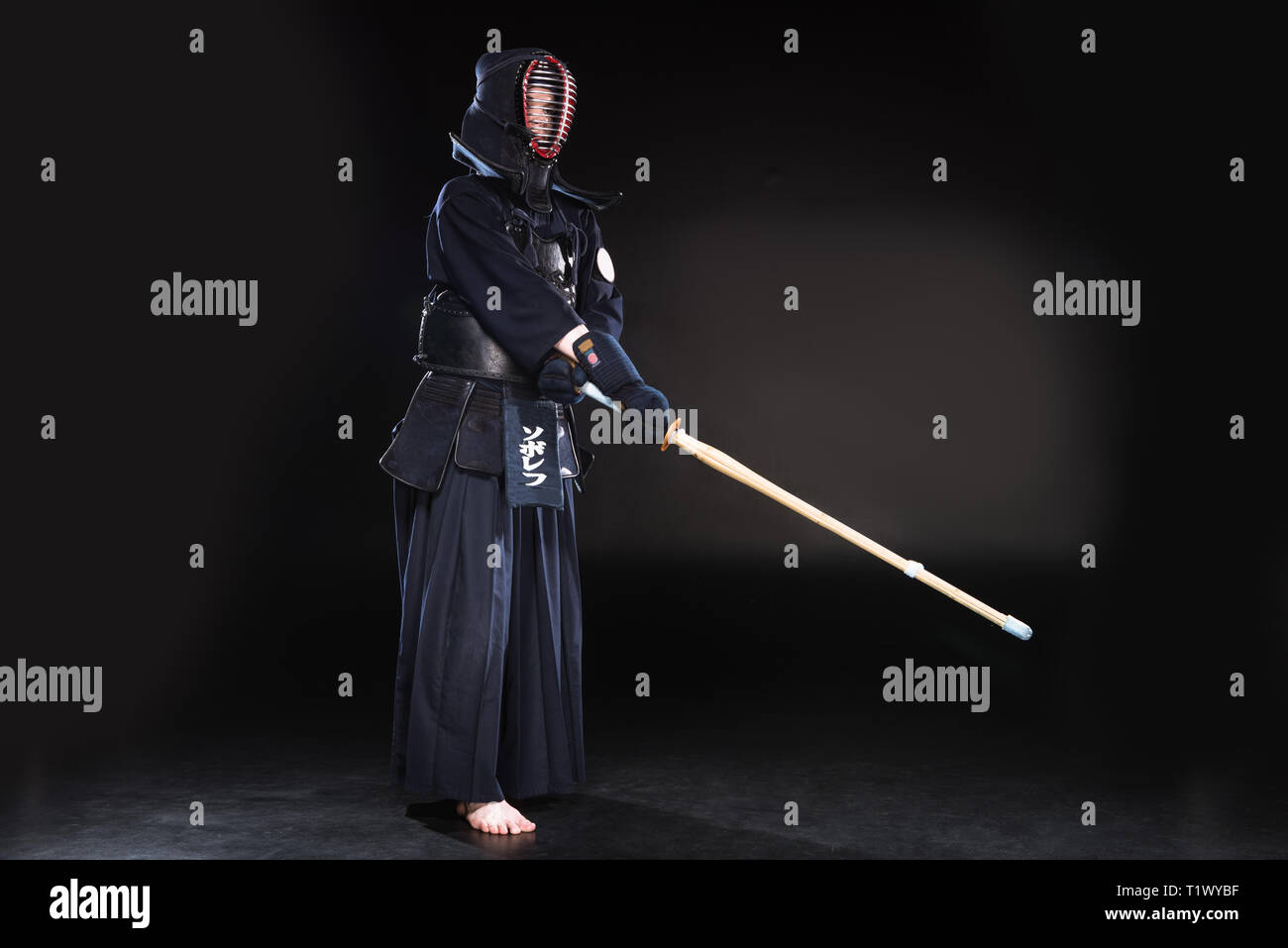 Full length view of kendo fighter in armor practicing with bamboo sword ...