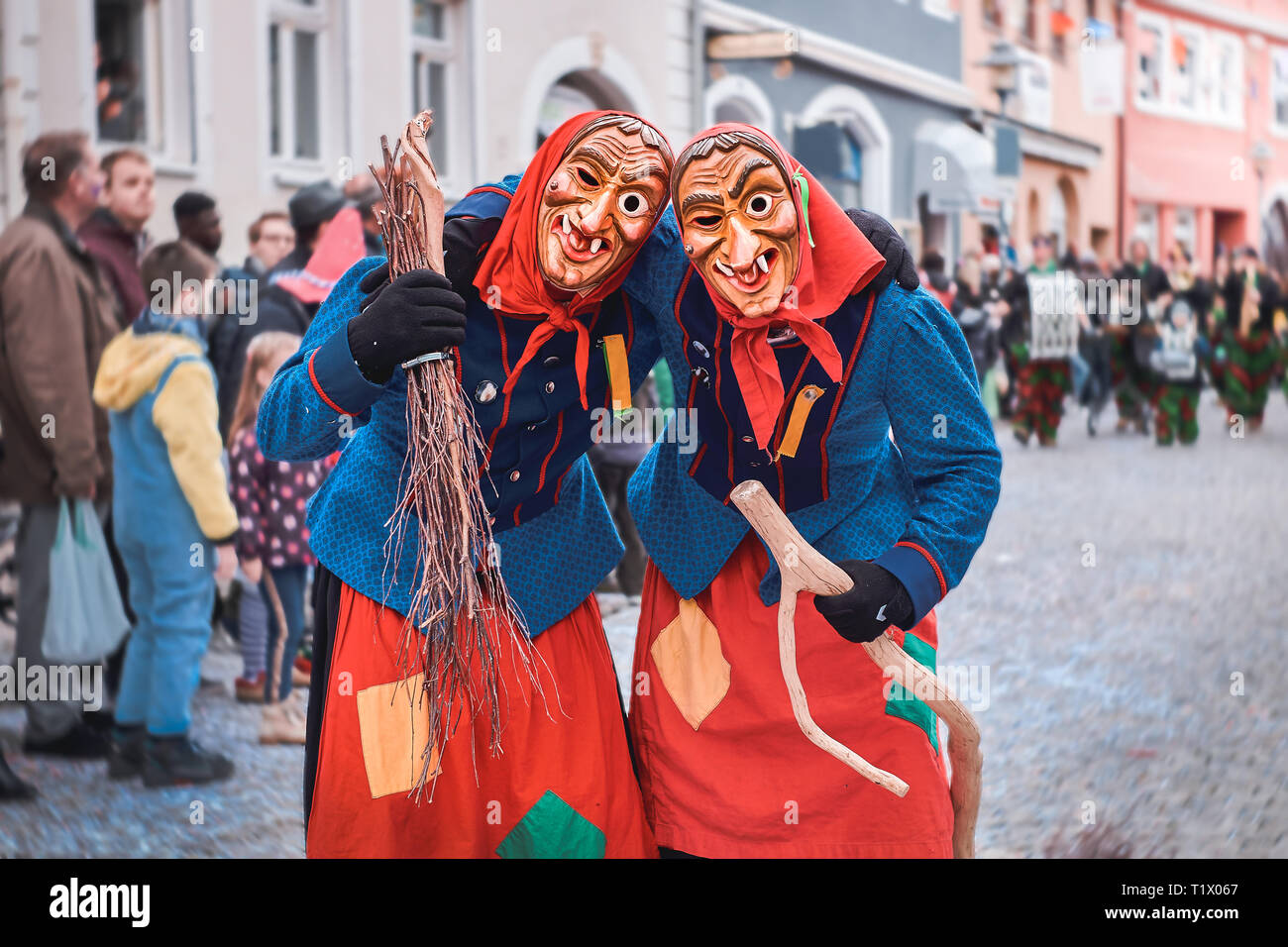 Two funny witches in a red and blue robe hug each other. Street ...