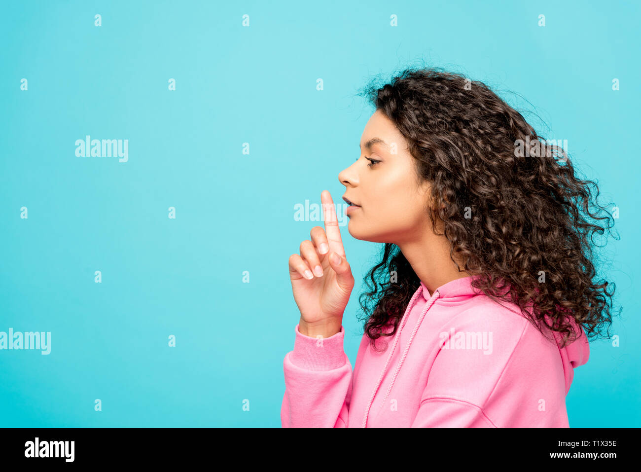 side view of curly african american girl showing hush sign isolated on ...