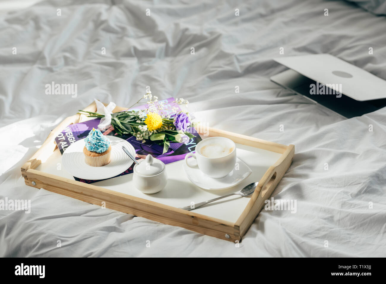 laptop near wooden tray with tasty breakfast on bed Stock Photo - Alamy