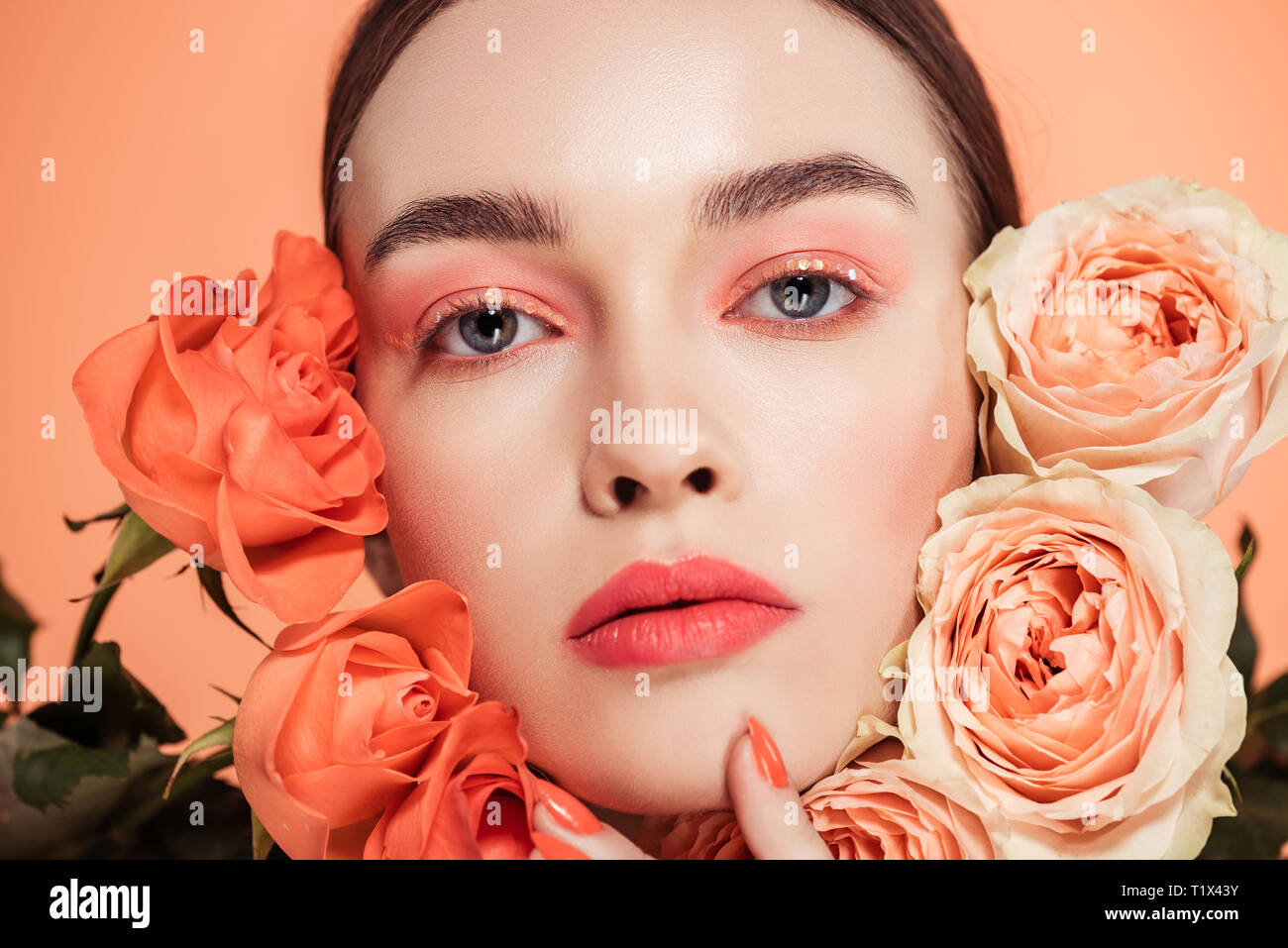 beautiful fashionable girl posing with rose flowers isolated on coral ...