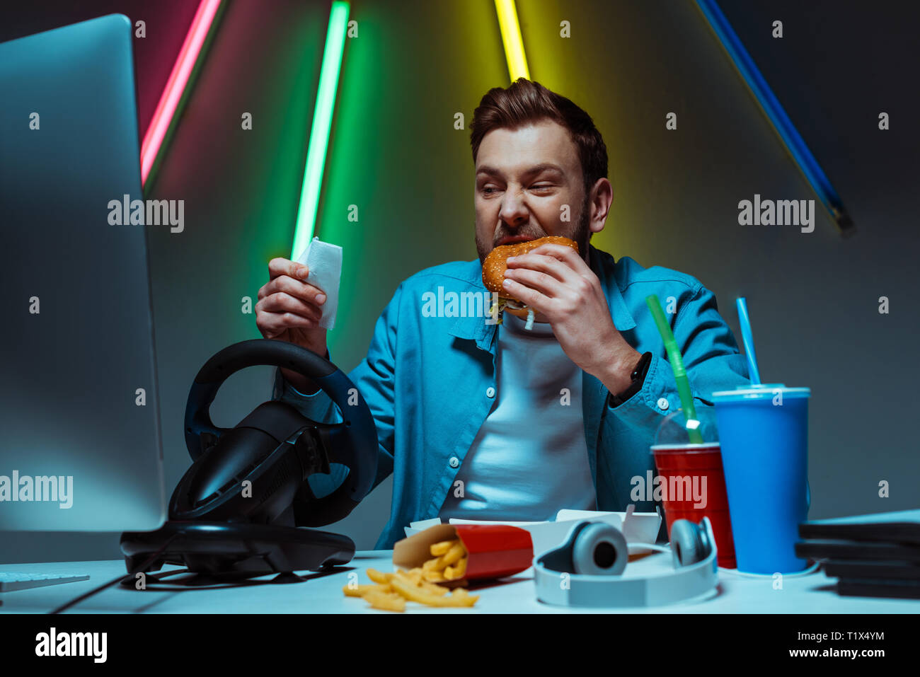 handsome and good-looking man eating burger and looking at computer ...