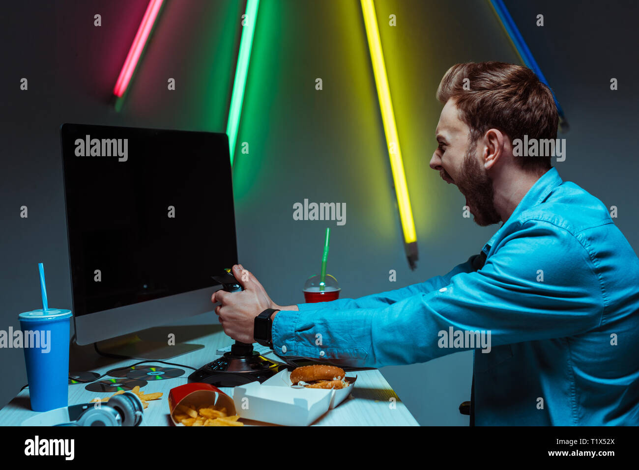 handsome and angry man screaming, holding joystick and looking at ...