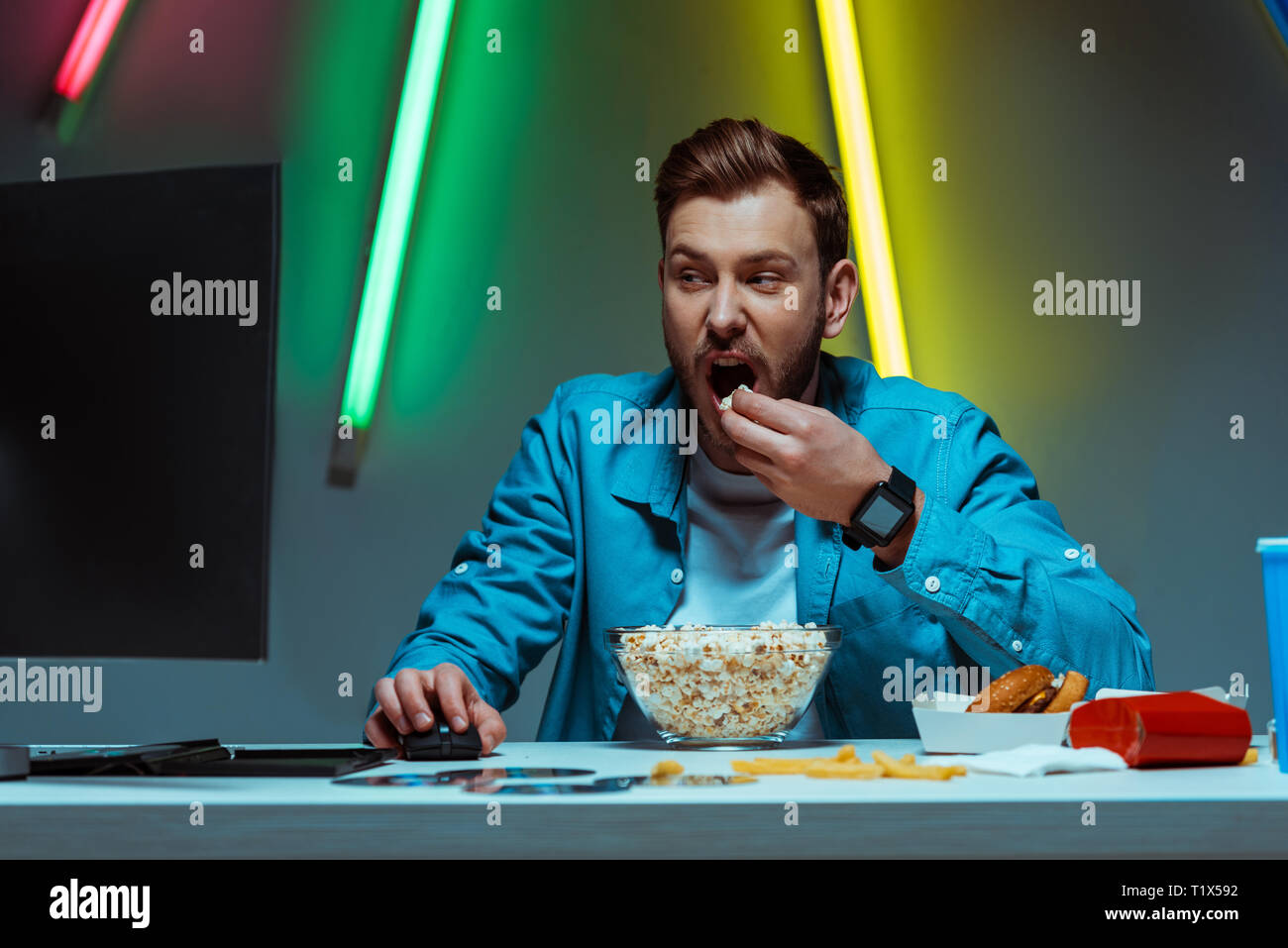 handsome and good-looking man holding computer mouse and eating popcorn ...