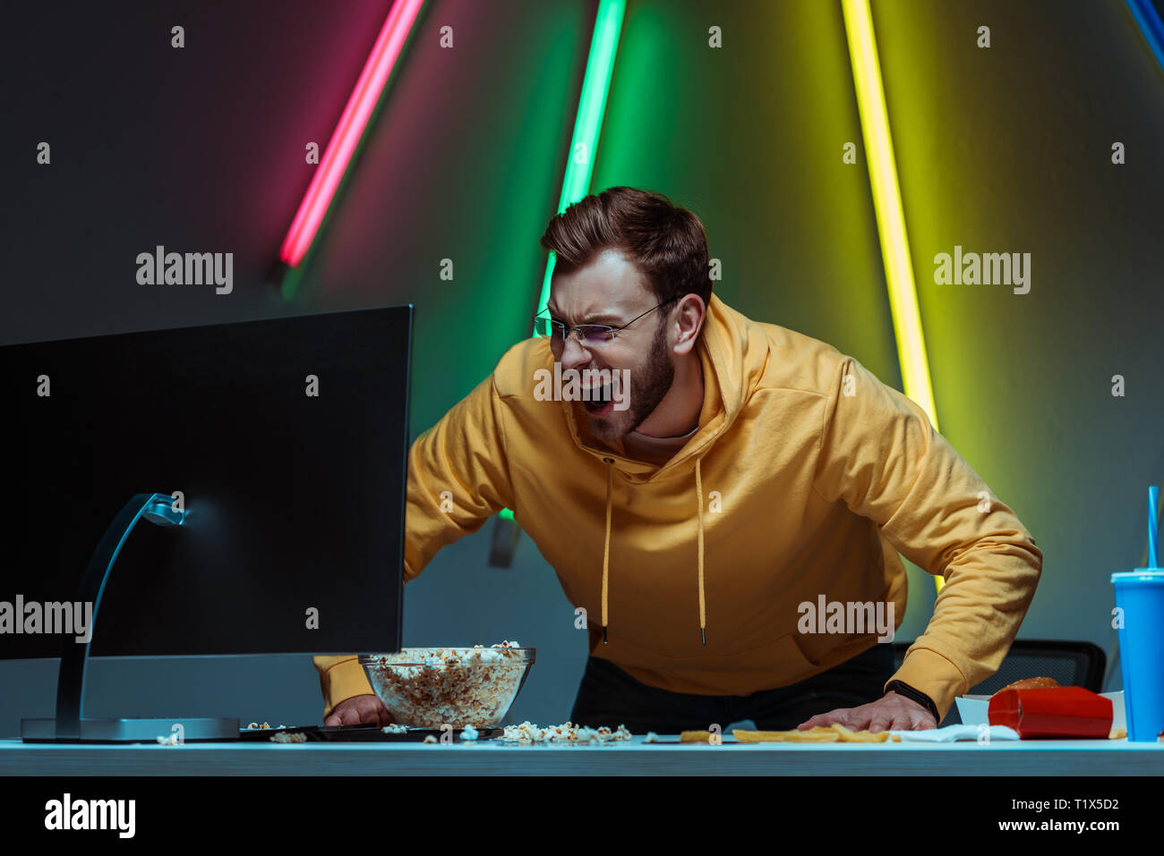 angry and good-looking man in glasses screaming and looking at computer ...