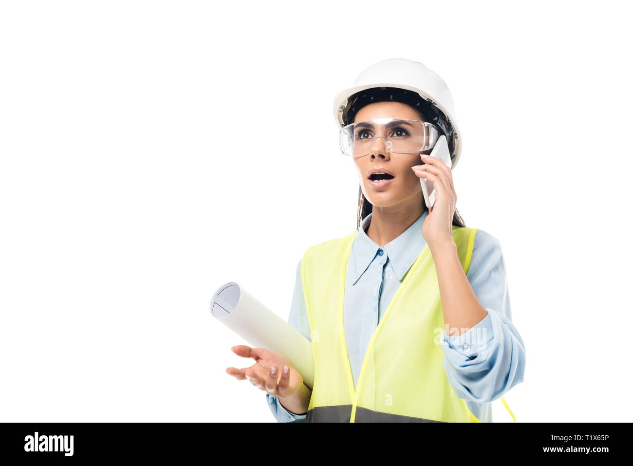 Shocked engineer in hardhat holding blueprint and talking on smartphone ...