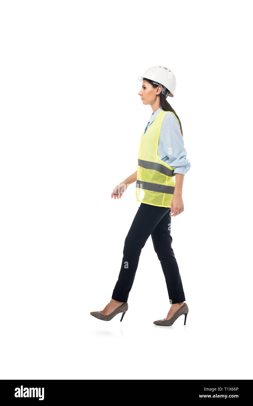 Side view of engineer in safety vest and high-heeled shoes walking ...