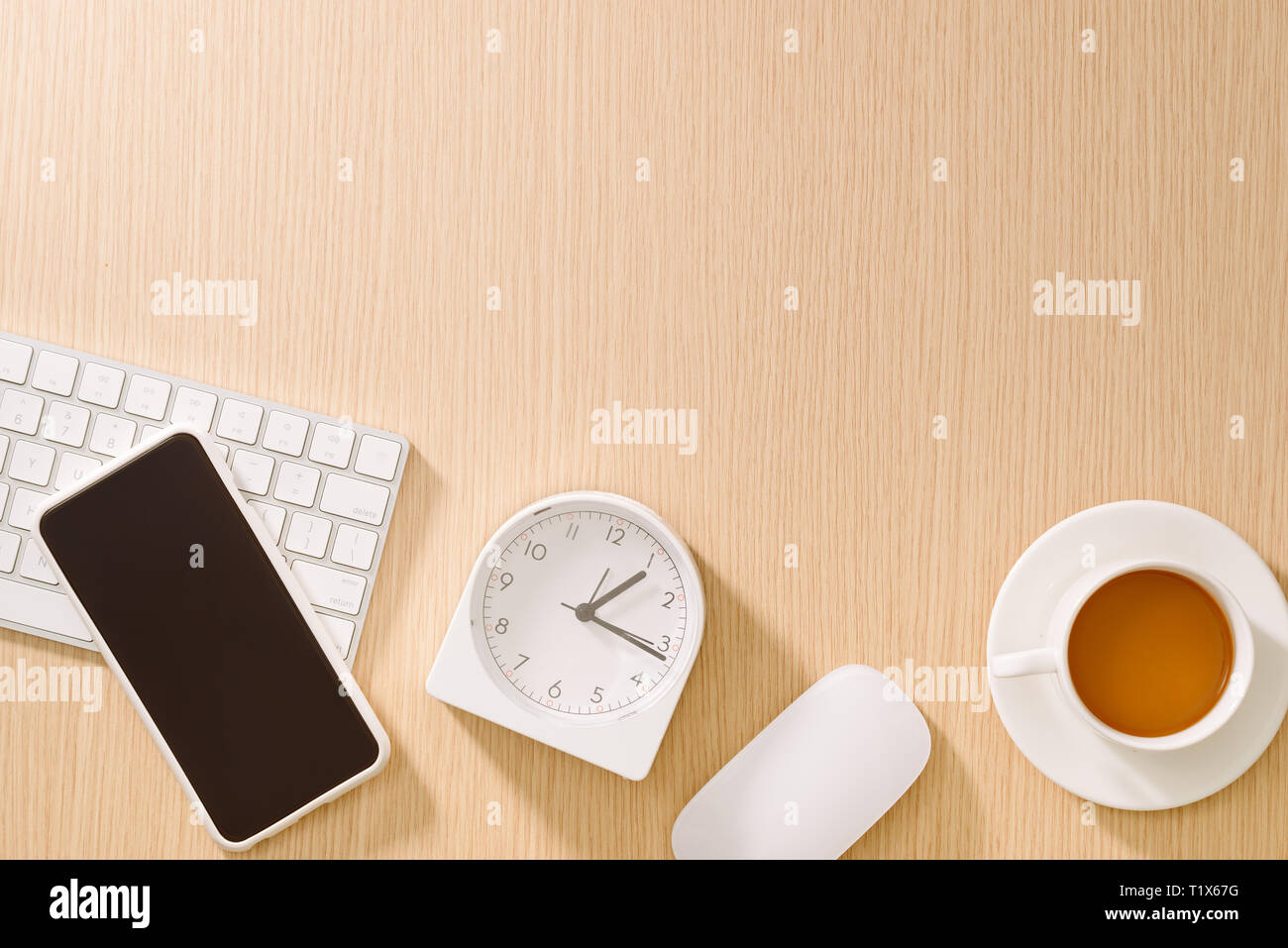Modern white office desk with keyboard, mouse, clock, cellphone, pen ...