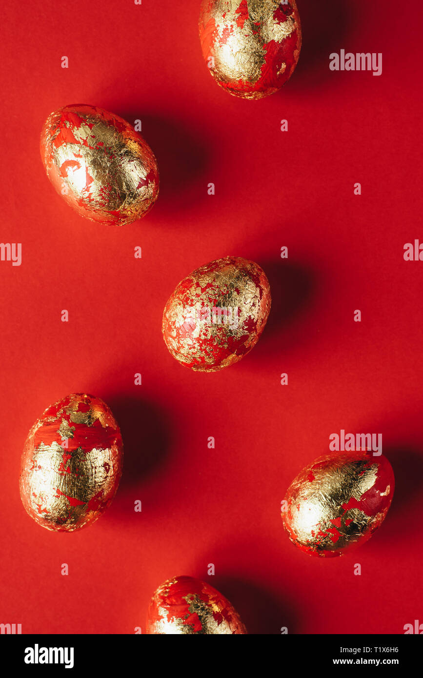 Six golden colored and decorated with sparkles Easter eggs on red ...