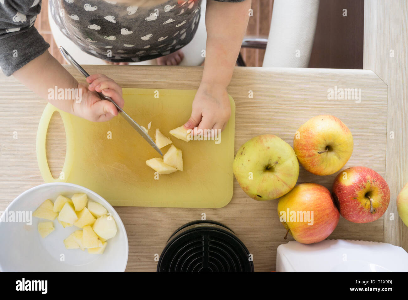 Child helps mother to cut apples for preparing fruit smoothie Stock ...