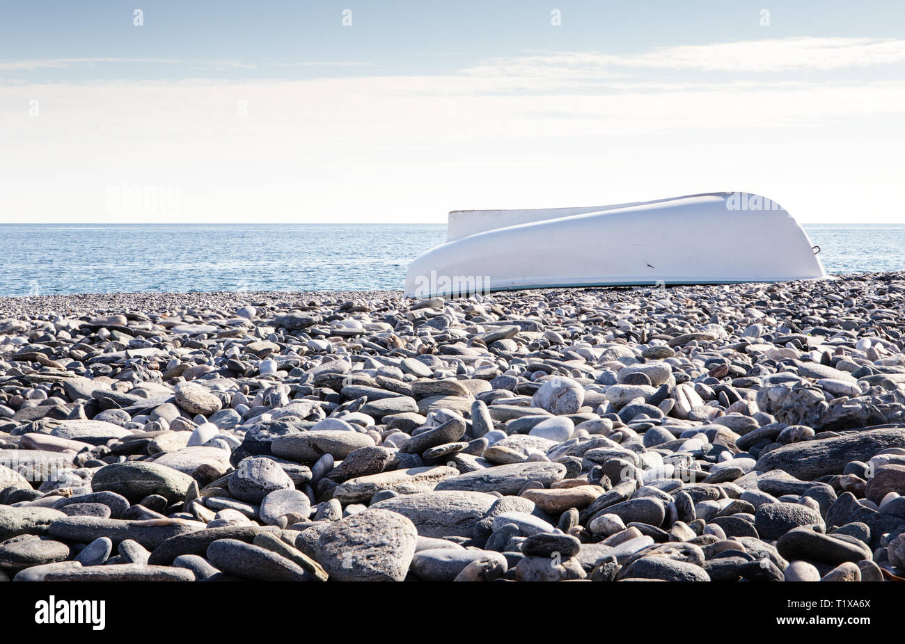 single upside down boat resting on a stony beach Stock Photo - Alamy