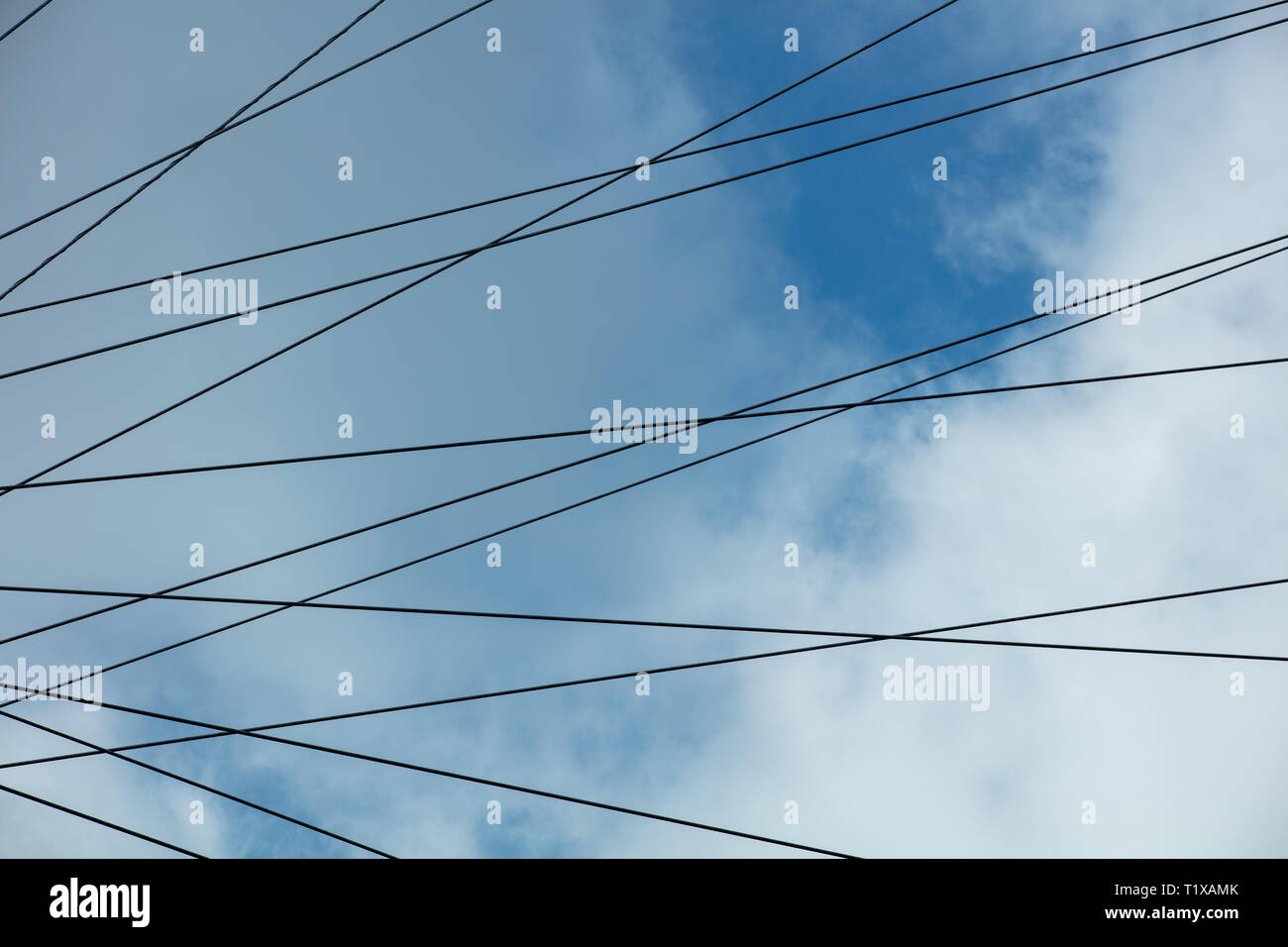 Diagonal man made metal wires cross each other in front of the blue sky ...