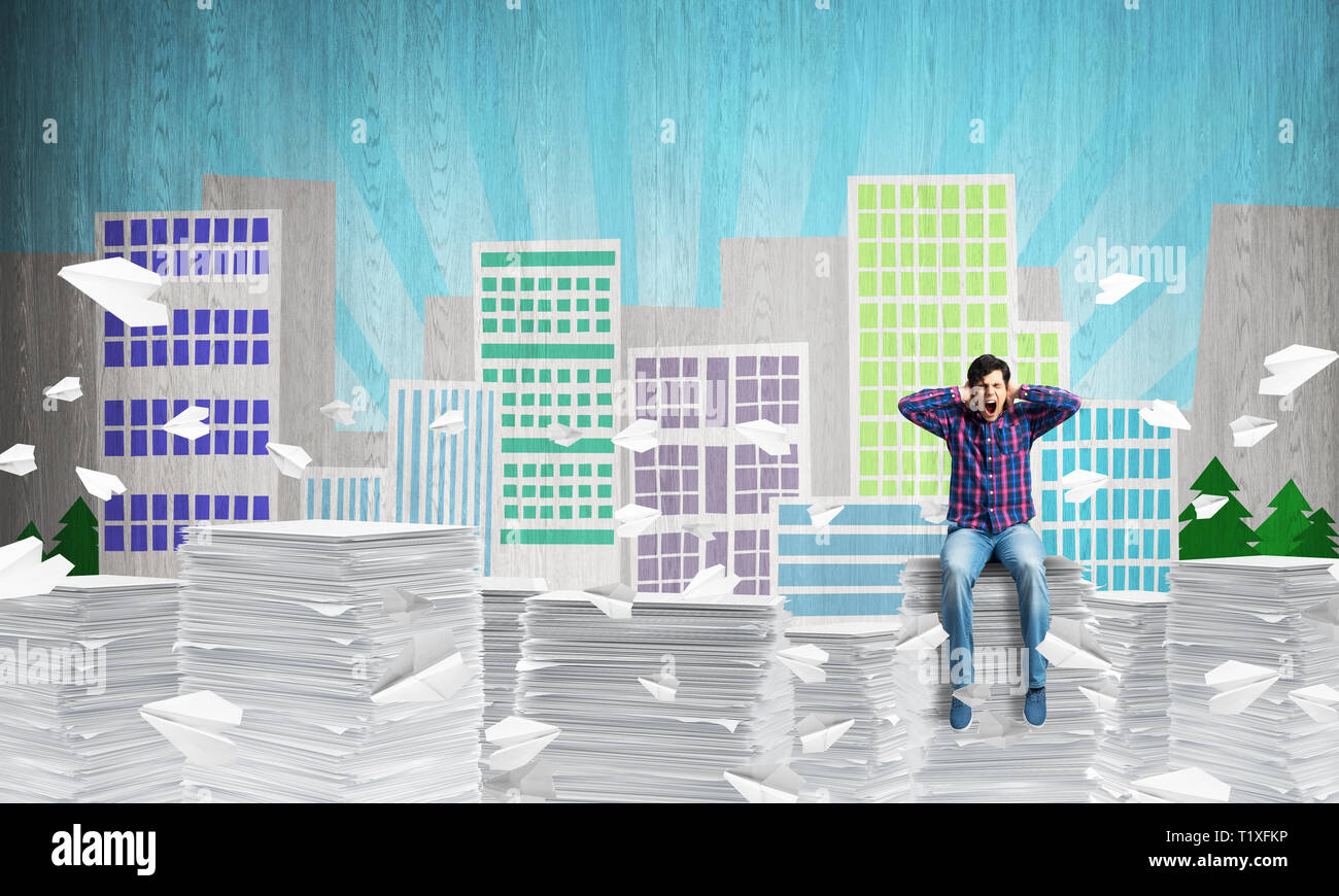 Young man sitting on pile of paper documents Stock Photo - Alamy